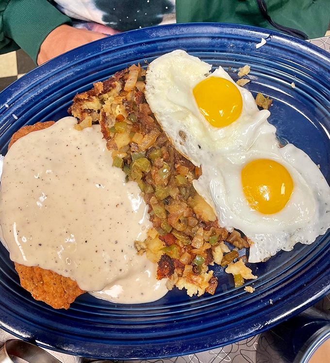 The country fried steak in its natural habitat—smothered in peppery gravy with eggs standing guard. A breakfast that says, "You won't need lunch today."
