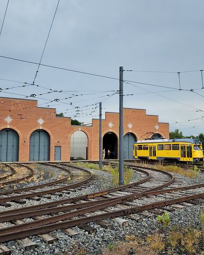 The yellow trolley emerges from the brick car barn like a time traveler arriving from the past. Those overhead wires weren't just decoration!