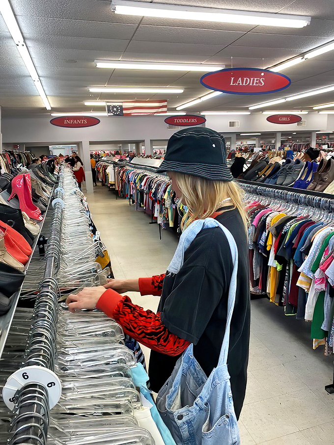 The serious business of thrifting requires proper headgear and focus. This shopper navigates the racks with the precision of a seasoned pro.