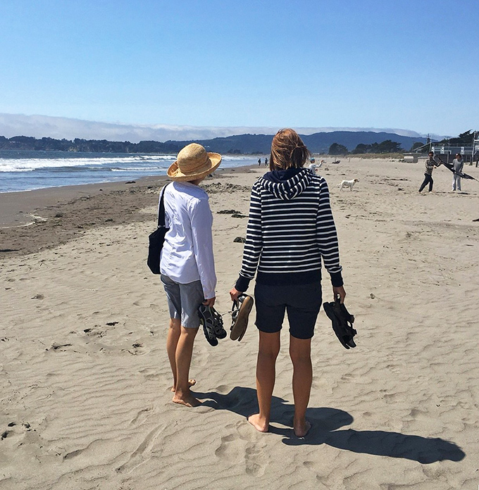 Barefoot wanderers finding their path along Stinson's shore. Sometimes the best adventures begin when the shoes come off.