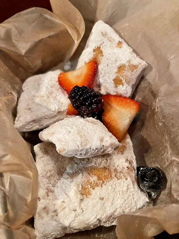 Beignets buried in powdered sugar like New Orleans after a sweet snowstorm. These pillowy delights are worth the inevitable white dust on your black shirt.