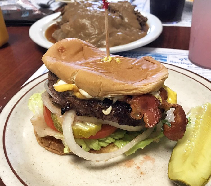 This isn't just a burger—it's a towering achievement of beef, bacon, and fresh toppings that requires a game plan before the first bite.