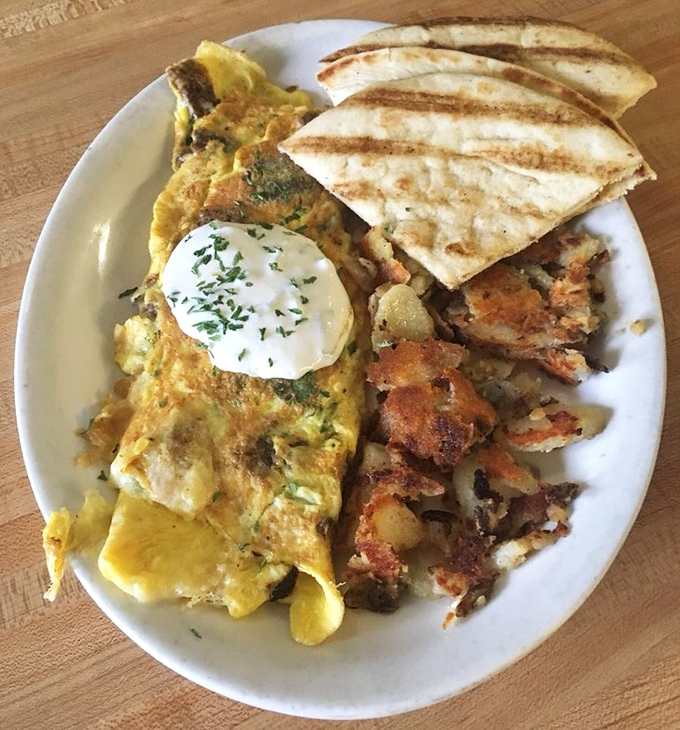 Brunch perfection captured on a plate&mdash;an omelet with enough fillings to qualify as a standalone meal, crispy potatoes, and grilled pita triangles.