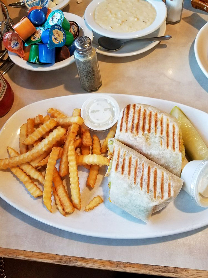 A perfectly grilled wrap flanked by crispy fries – the lunch option that makes breakfast regulars consider a later arrival.