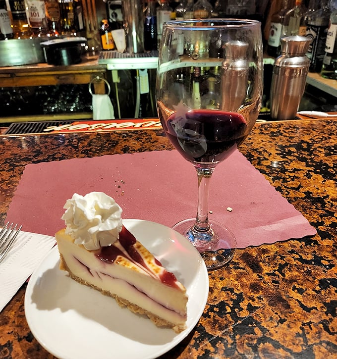 A slice of berry-swirled cheesecake paired with red wine &ndash; because sometimes dessert isn't just a course, it's a life philosophy.