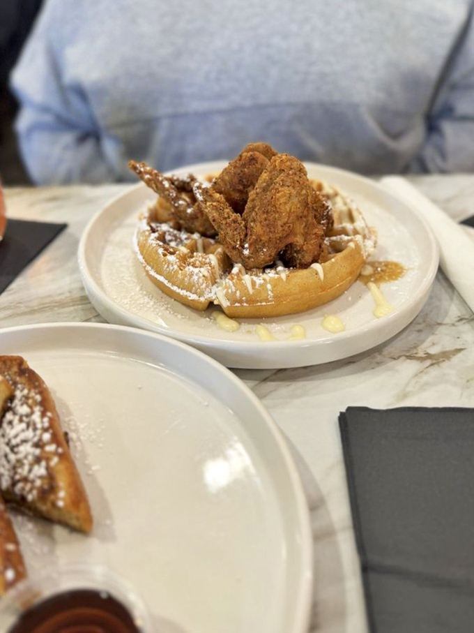 Southern hospitality on a plate: golden fried chicken wings perched atop a waffle throne, dusted with powdered sugar&mdash;a sweet and savory alliance that never disappoints.