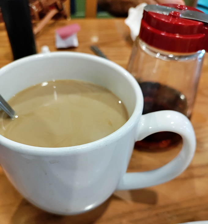Coffee served in a proper mug&mdash;not those dainty cups that leave you wanting. The red sugar dispenser stands ready for those who need the sweet balance.