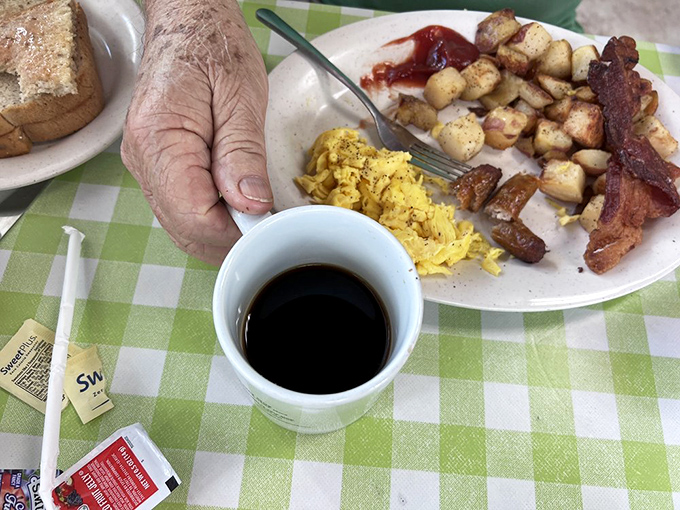 The breakfast trinity: strong coffee, perfectly scrambled eggs, and home fries that somehow taste better on those green checkered tablecloths.