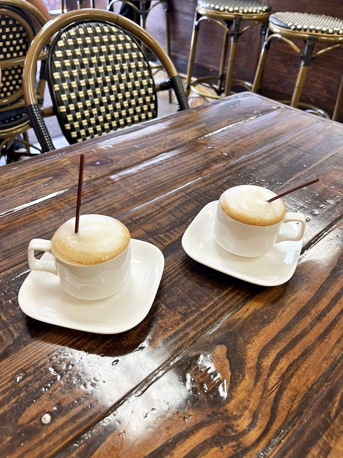Two cortaditos await conversation on a weathered wooden table, their creamy tops promising the perfect balance of espresso intensity and sweet milk.