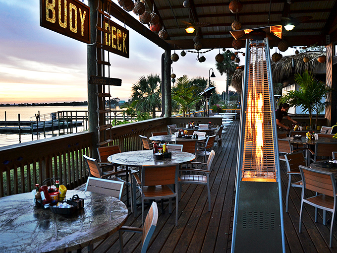 As twilight descends, the deck transforms. Heat lamps glow, the "Buoy Deck" sign illuminates, and the Indian River becomes a mirror for the sunset.