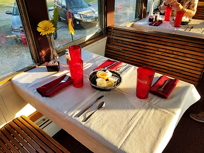 Dining by rail&mdash;where the scenery changes but the elegance remains constant. Those red glasses add a touch of vintage glamour to your rolling feast. 
