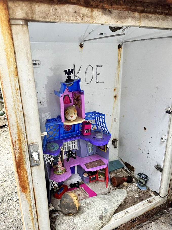 Even abandoned dollhouses find new purpose here&mdash;a miniature world tucked inside a rusty refrigerator door becomes an unexpected moment of whimsy.