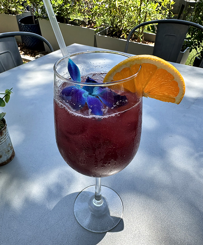 This isn't just a cocktail&mdash;it's a sunset in a glass, garnished with blue petals and promises of vacation decisions you won't regret in the morning.