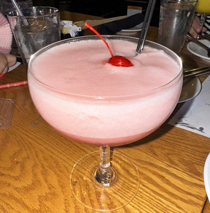 A frothy pink cocktail topped with a cherry—proof that sometimes the most serious culinary establishments know how to have a little fun in a glass.