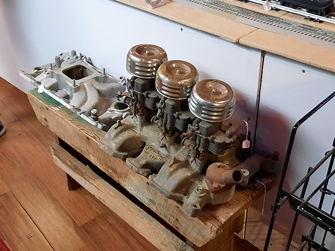 Mechanical poetry in metal and grease. Car enthusiasts will recognize this triple-carb setup as automotive artwork from a simpler time.
