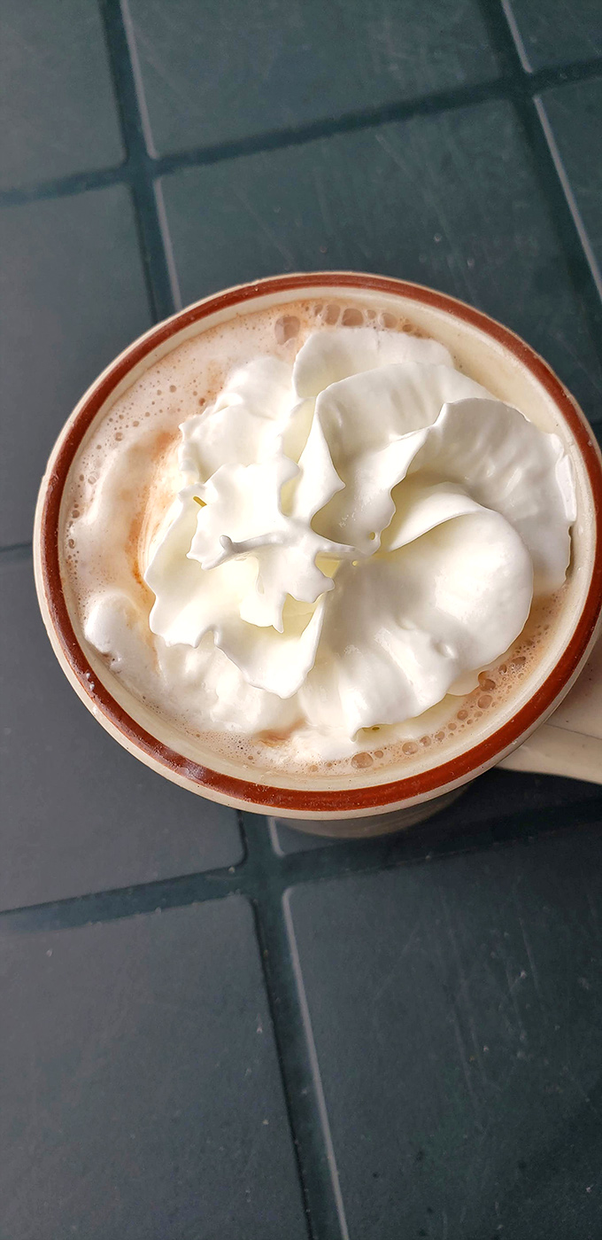 A mountain of whipped cream crowns this hot beverage, creating the perfect morning indulgence that's worth every delicious calorie.