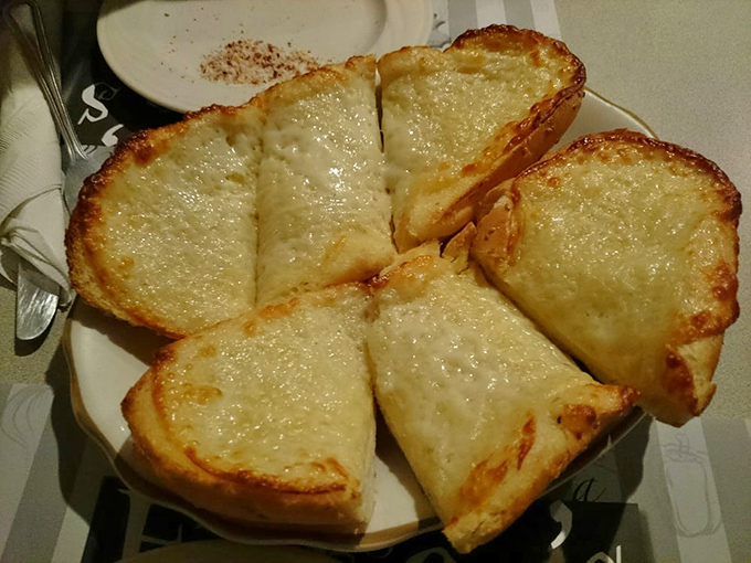 Garlic bread with cheese that stretches from plate to mouth like it's auditioning for a mozzarella commercial.
