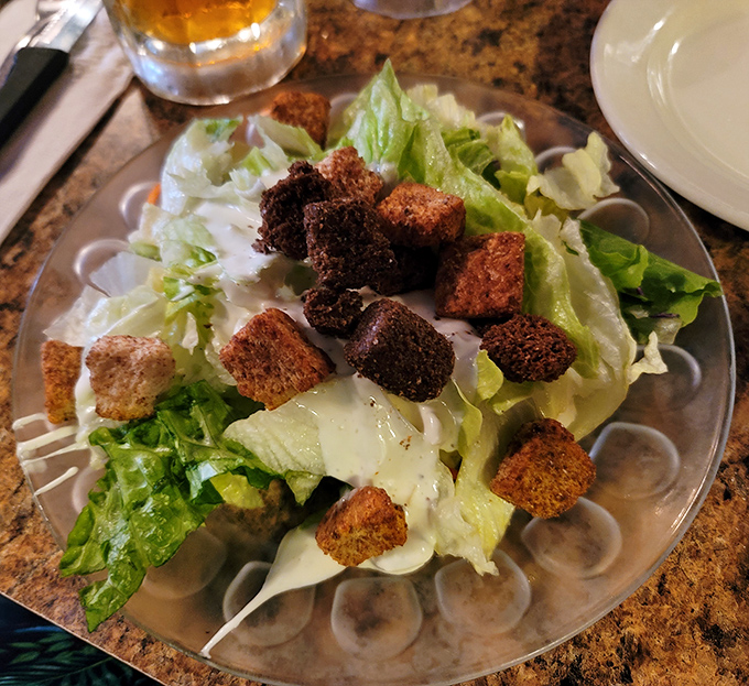 A proper house salad that understands its role: crisp, fresh, and adorned with croutons that crunch like autumn leaves.