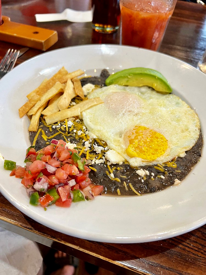 Huevos Rancheros: where breakfast meets fiesta. That sunny-side egg perched atop black beans is practically begging for your fork's attention.