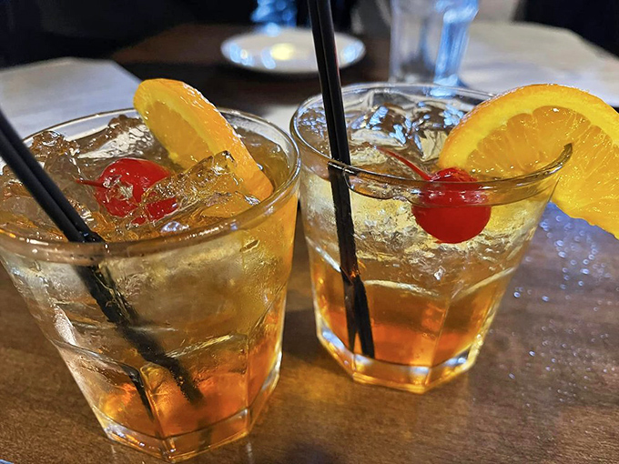 Two Wisconsin Old Fashioneds waiting patiently for their moment – liquid sunshine garnished with proper fruit and zero pretension.