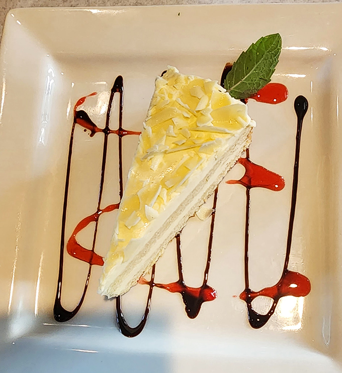 A slice of key lime pie artfully presented with chocolate and berry sauce—because dessert should always be dressed better than you are.