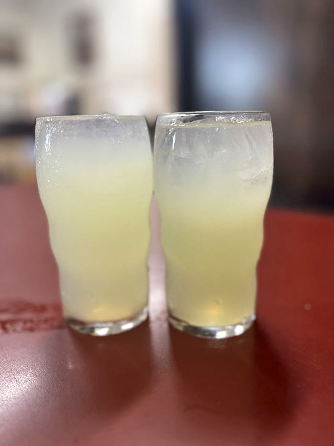 Two glasses of lemonade sitting pretty on the red tabletop&mdash;the perfect sweet-tart counterpoint to the savory sandwich experience.