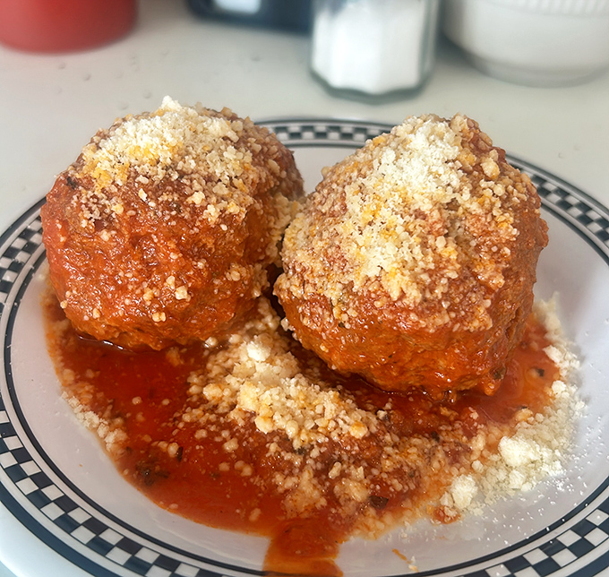 These meatballs aren't just swimming in tomato sauce, they're taking a luxurious spa bath in it &ndash; crowned with a snowfall of parmesan.