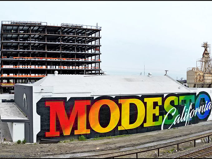 This vibrant rainbow-colored mural proudly announces "MODESTO California," transforming an industrial wall into an Instagram-worthy welcome sign.