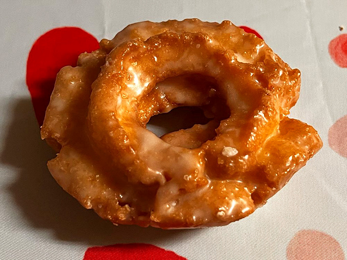 The rustic appeal of a perfectly executed classic. This old-fashioned donut, with its characteristic cracks catching pools of glaze, is comfort food elevated to an art form.