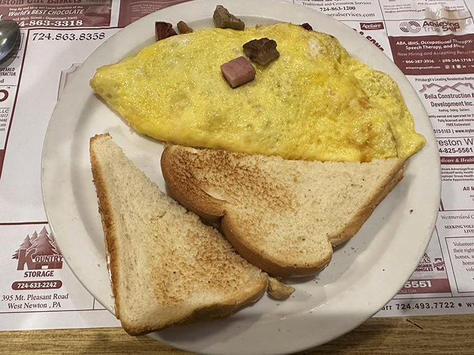 The humble omelet, elevated to art form &ndash; folded around savory ham chunks and served with toast that's achieved that perfect golden-brown sweet spot.