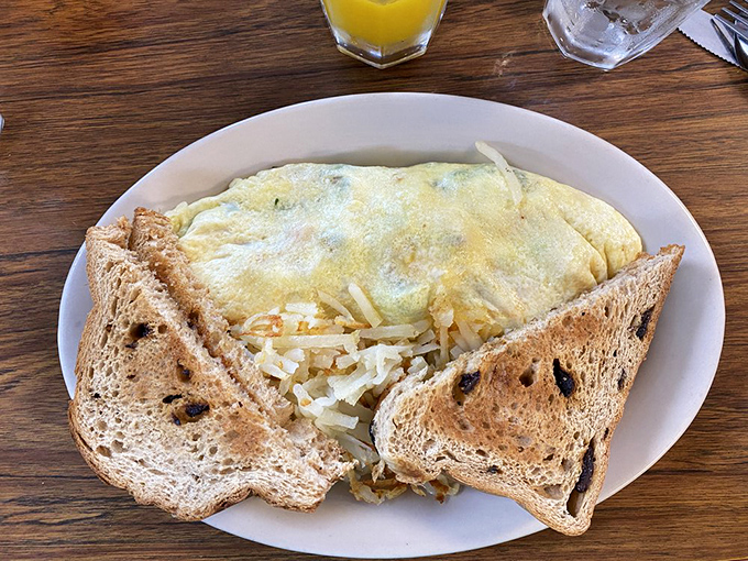 This omelet doesn't need fancy credentials—just perfectly folded eggs embracing a medley of vegetables and toast standing by for the overflow.