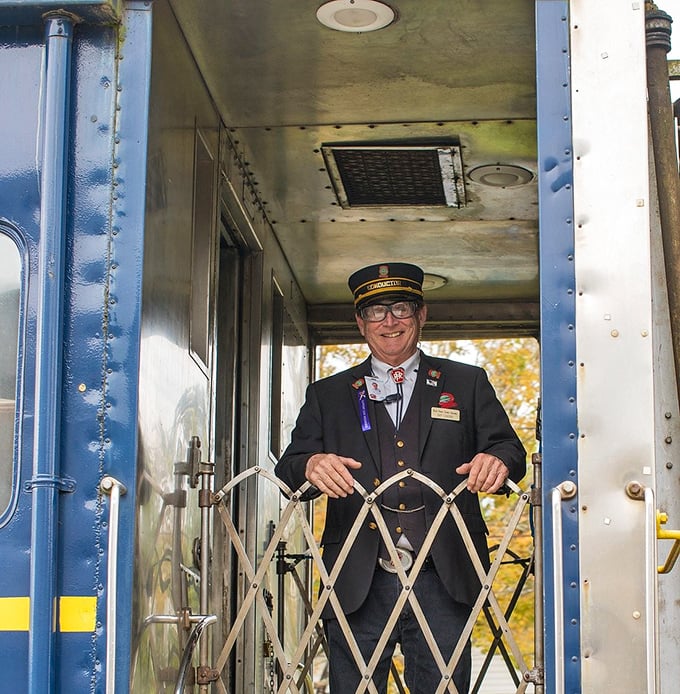 The conductor's smile says it all—part ambassador, part storyteller, part guardian of a cherished American tradition rolling through the hills.