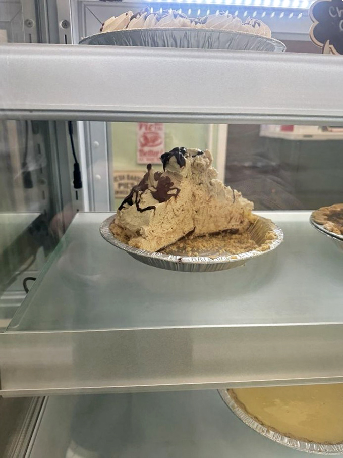 Peanut butter pie with chocolate drizzle sits regally in the display case, daring you to walk away without surrendering to its siren call.