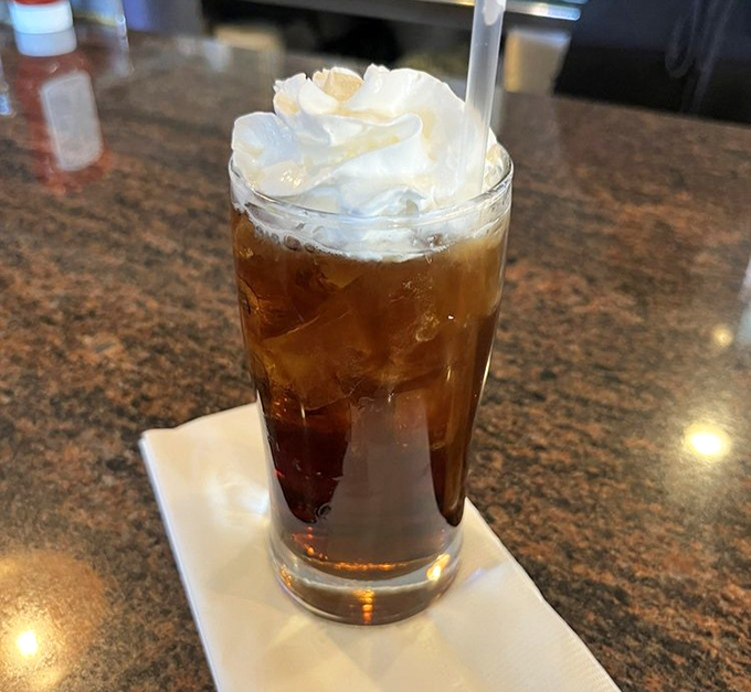 The root beer float arrives like a childhood memory in glassware, topped with a cloud of whipped cream that makes adulting seem temporarily optional.