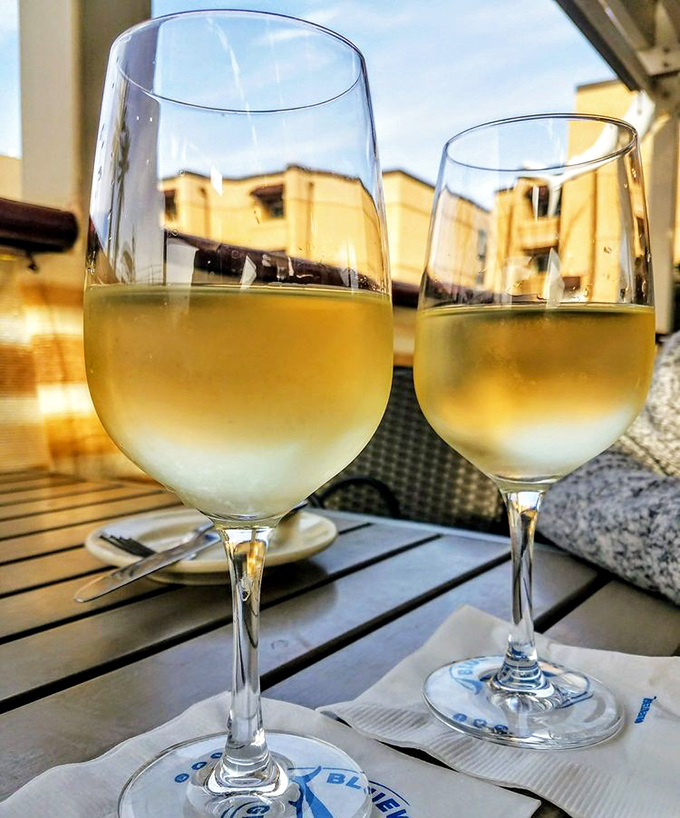Two glasses of crisp Sauvignon Blanc catching the golden hour light&mdash;because seafood without wine is like a day without sunshine.