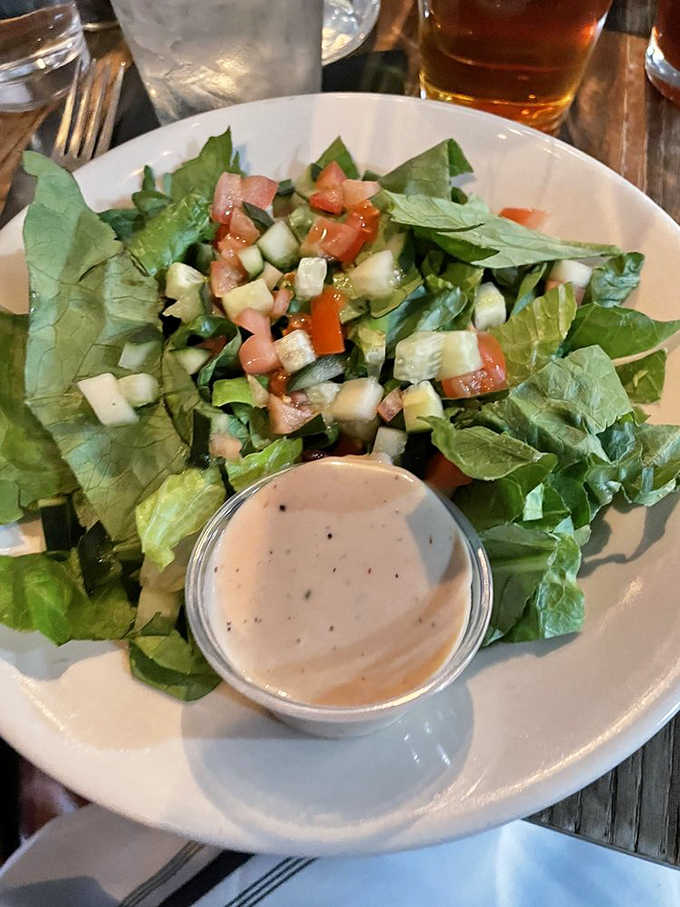 This isn't just a side salad; it's a thoughtful composition of garden-fresh ingredients with a dressing that makes you wonder if they'd sell it by the bottle.