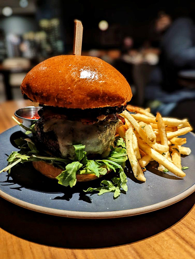 This isn't just a burger; it's architecture. A cathedral of beef crowned with a glossy brioche dome and flanked by golden fry sentinels.