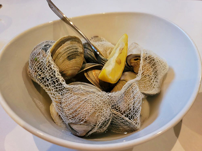 Steamed clams nestled in their broth like tiny treasures waiting to be discovered. That lemon wedge isn't just garnish&mdash;it's essential equipment.
