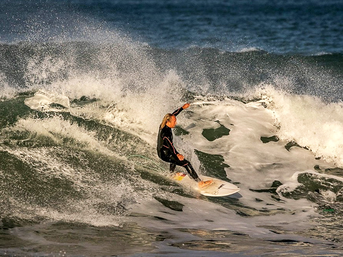 Local surfers catch waves with Morro Rock as their backdrop, living the California dream daily.