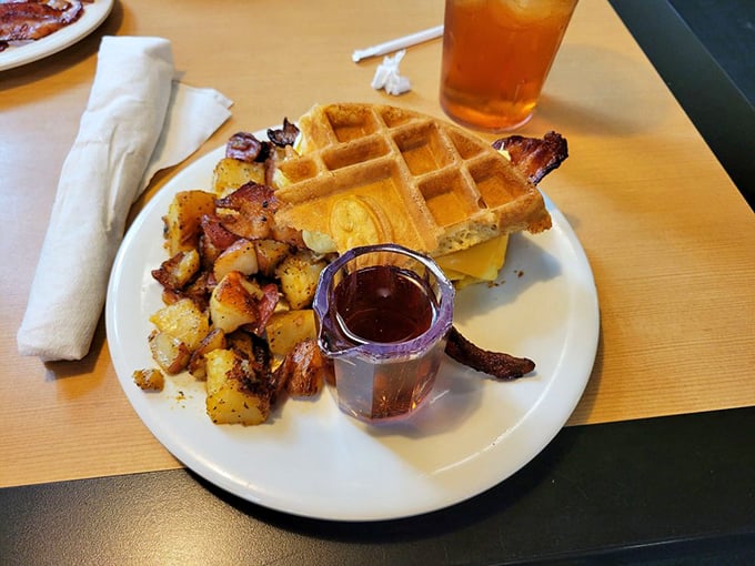 Breakfast architecture at its finest&mdash;golden waffle creating the perfect foundation for eggs and bacon. The tiny pitcher of syrup adds that touch of breakfast dignity.