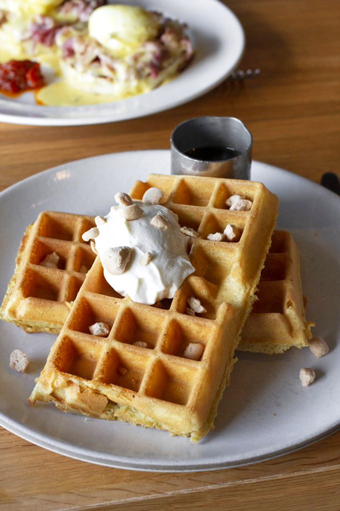 Golden waffles crowned with whipped cream and tiny crunchies&mdash;breakfast that makes you wonder why we don't eat dessert first every day.