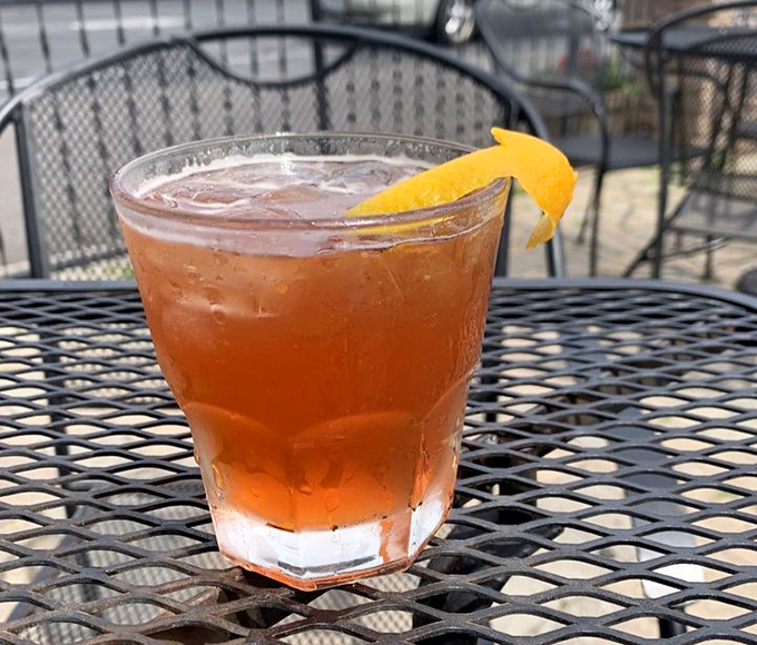 Patio sipping at its finest. This amber-hued cocktail, garnished with orange, isn't just a drink&mdash;it's liquid sunshine in Columbus's most charming outdoor space.