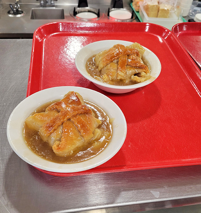 Apple dumplings swimming in warm sauce&mdash;proof that sometimes the most heavenly desserts come on humble cafeteria plates.