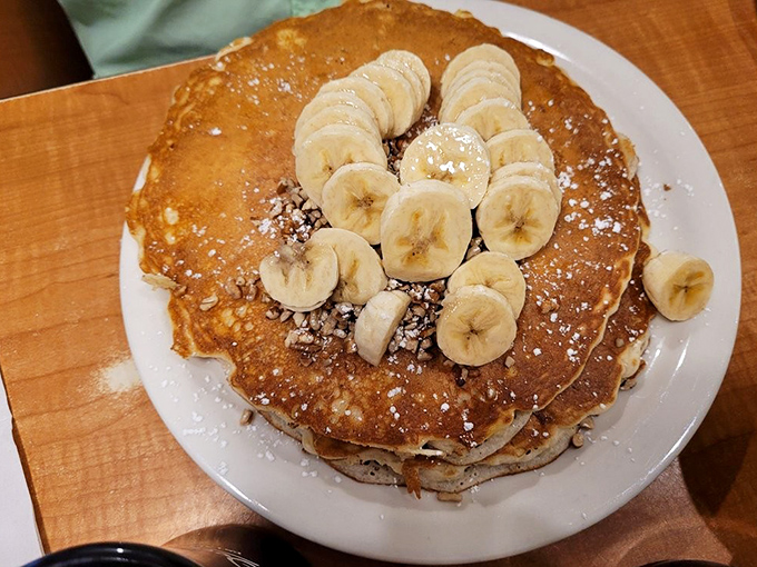 Pancakes stacked higher than my weekend reading pile, with bananas arranged like they're sunbathing on a carb beach.