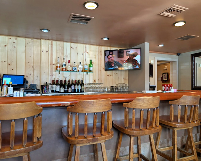 The bar at D'Carlos&mdash;where wooden stools await, spirits stand at attention, and the TV ensures you won't miss the game while savoring your pre-dinner Old Fashioned.