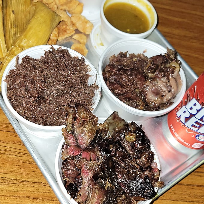 Tender, slow-cooked barbacoa displayed in containers shows the authentic preparation that creates this weekend-only treasure.