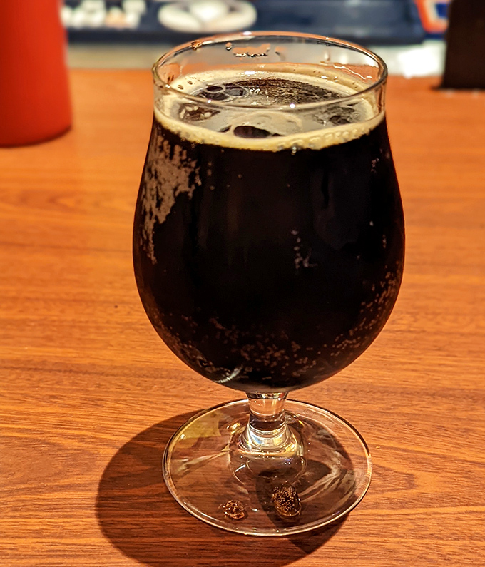 A dark, rich craft beer in proper glassware&mdash;because even when eating hot dogs, we deserve a touch of civilization.