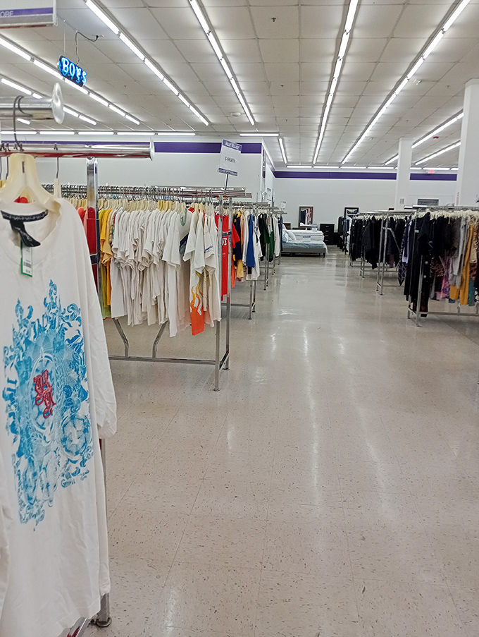 A large thrift store with neatly organized clothing racks under bright fluorescent lighting. 