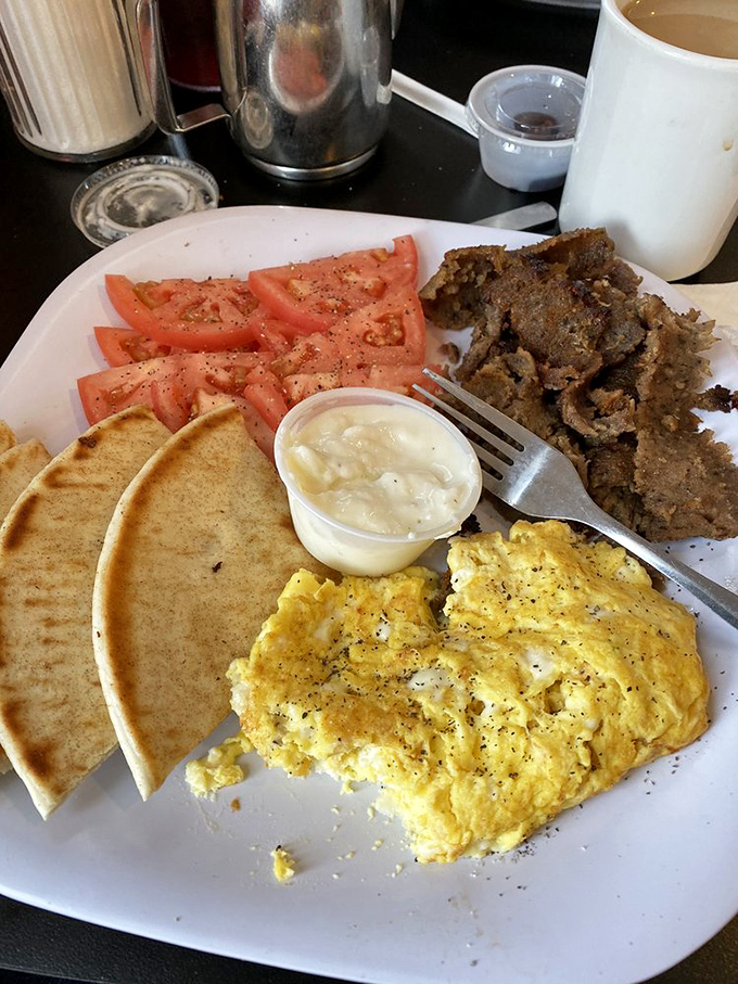 A breakfast platter that speaks the universal language of "you won't need lunch today" &ndash; eggs, pita, and seasoned meat in perfect harmony.