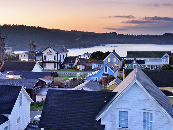 As sunset bathes the village in amber light, Mendocino's rooftops create a patchwork quilt of history, with water towers standing sentinel over it all.